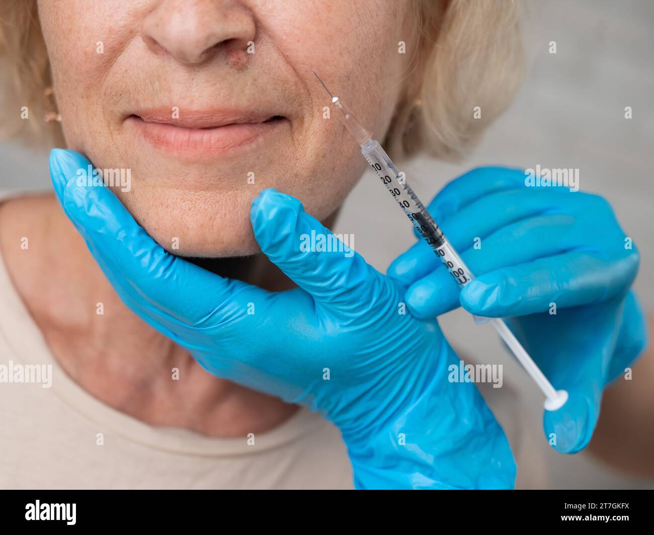 Doctor makes beauty injections in the face of an old caucasian woman ...