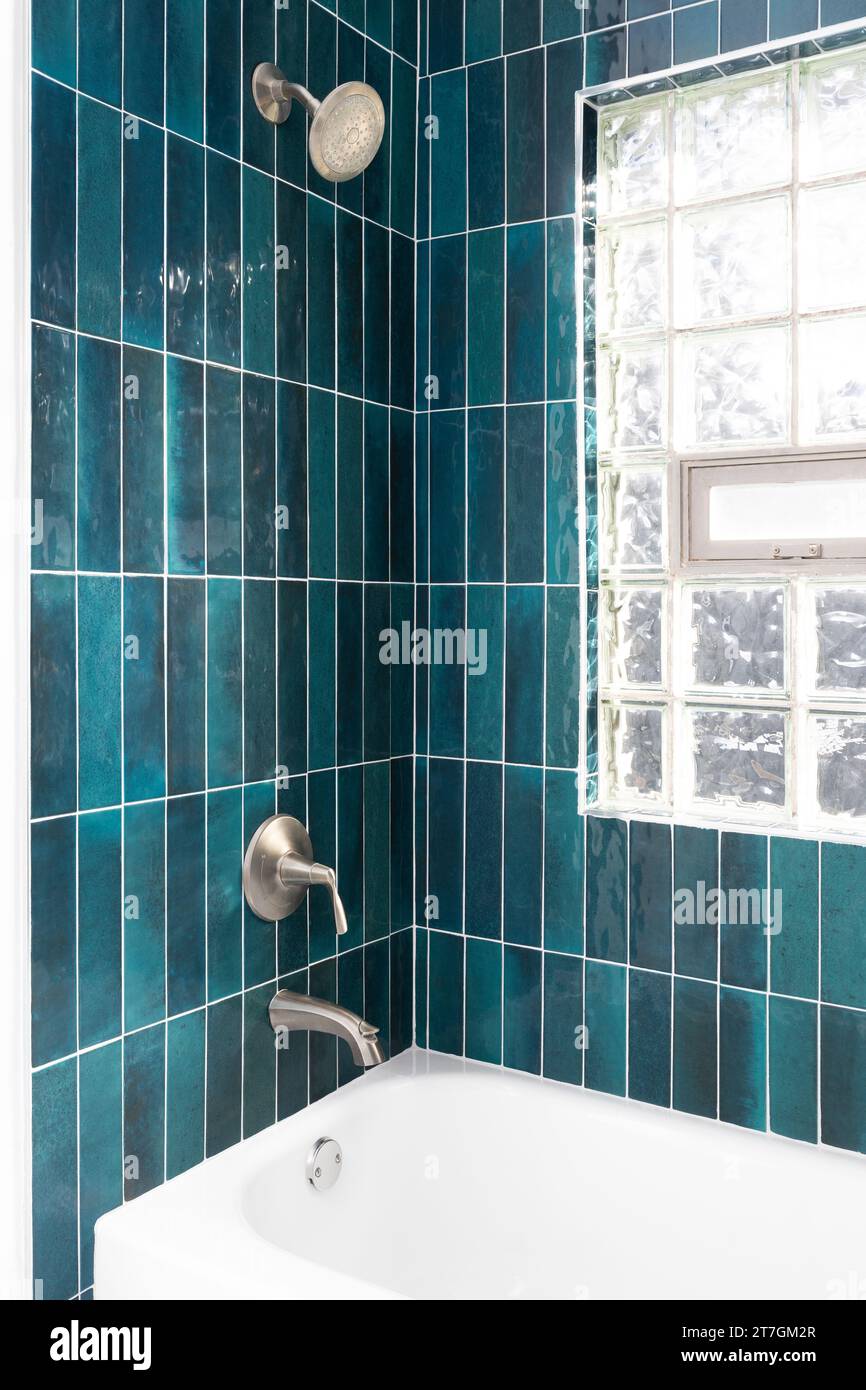 A bathroom shower detail with vibrant blue vertical glass subway tiles ...