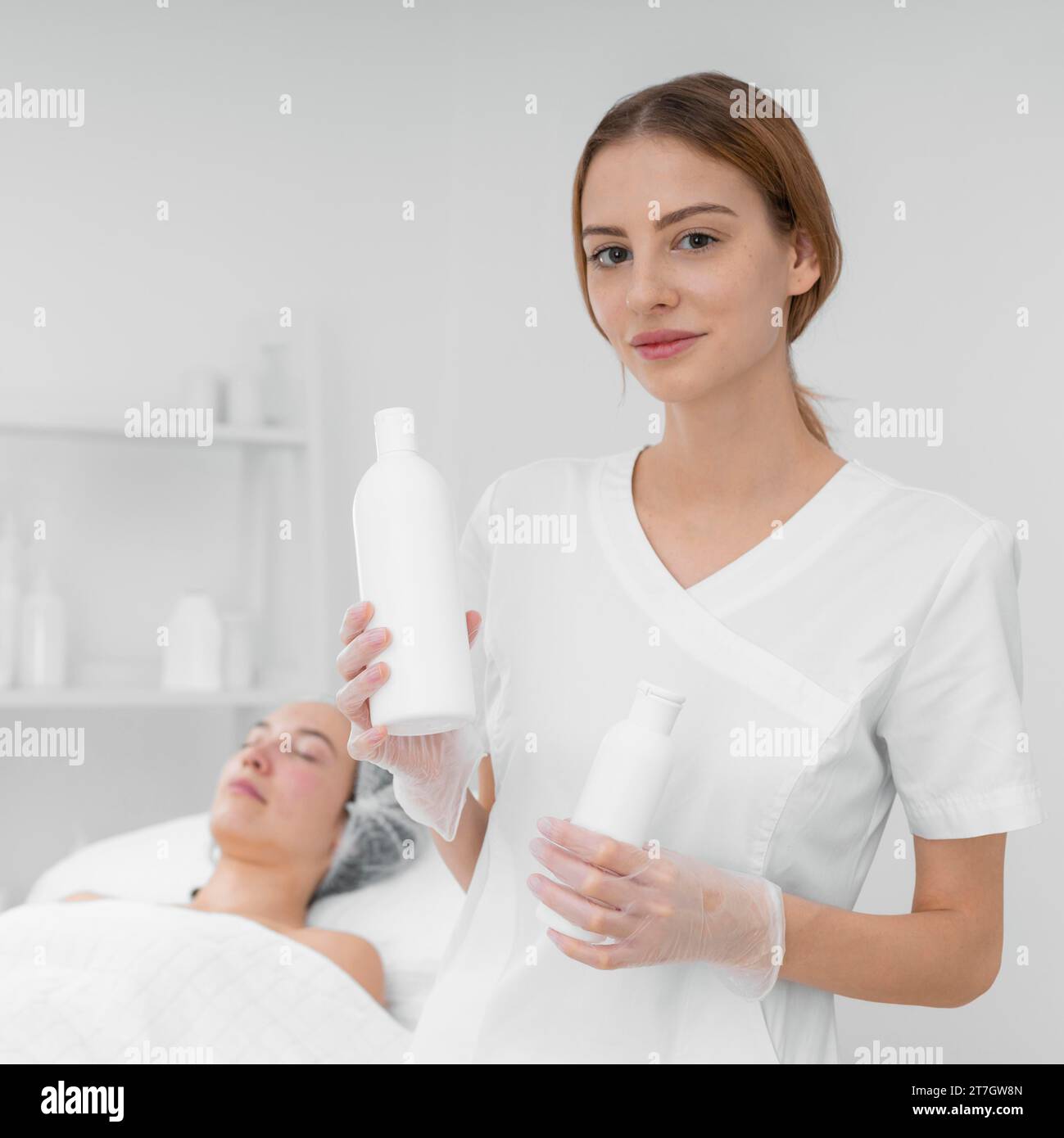 Beautician with lotion female client Stock Photo - Alamy