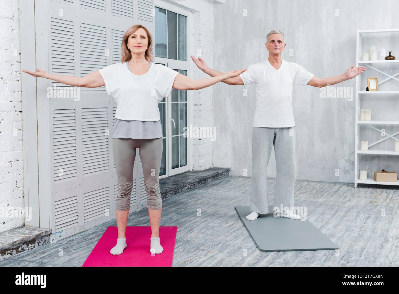 Couple performing yoga by outstretching arms standing yoga mat Stock ...