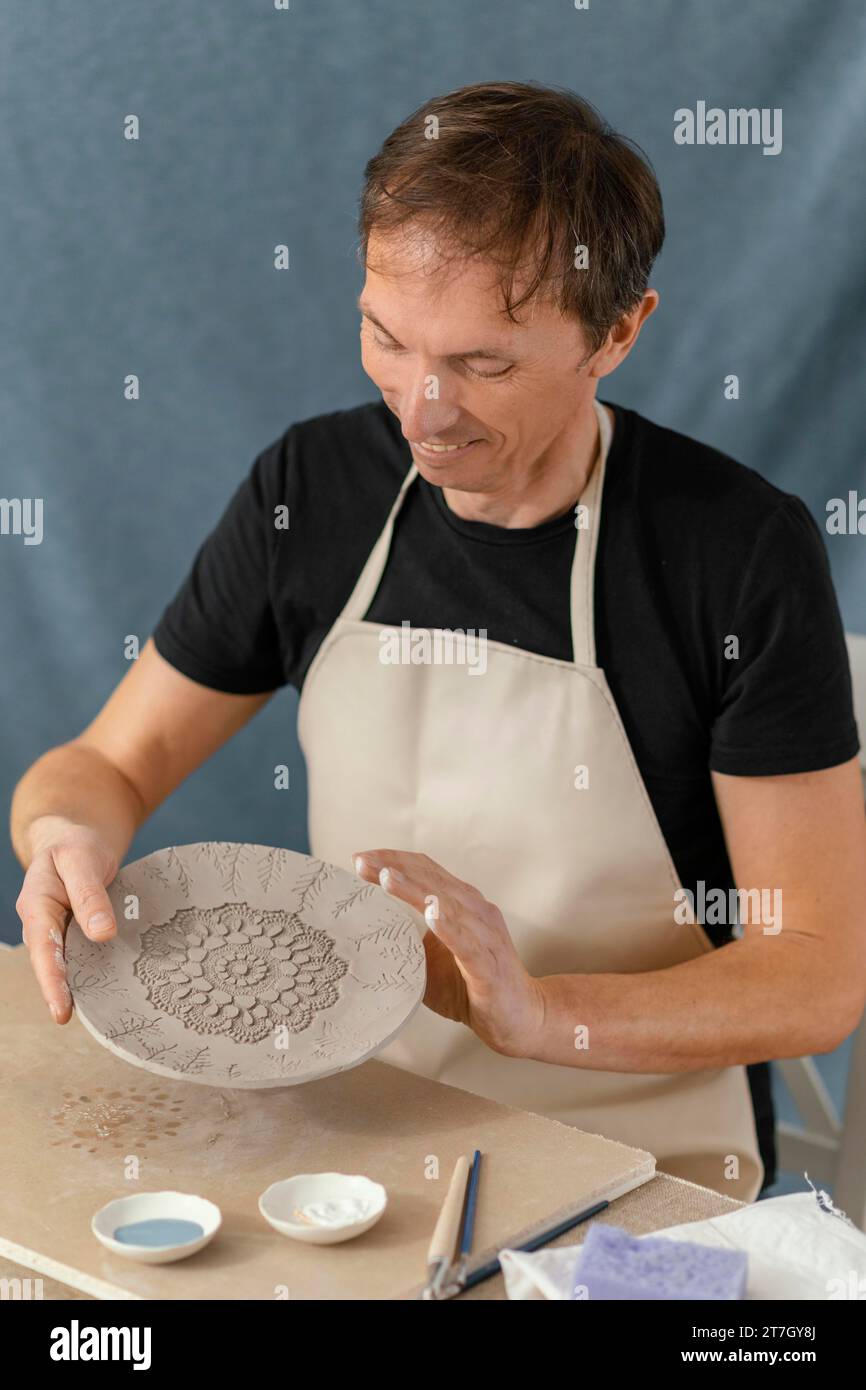 Medium shot smiley man doing pottery Stock Photo - Alamy