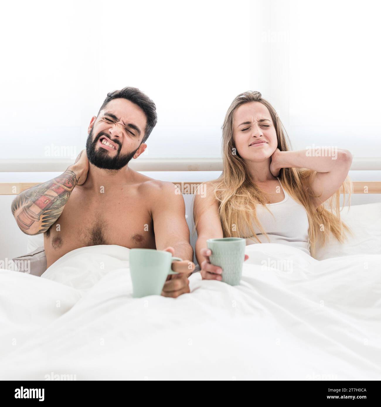 Young couple sitting bed with cup coffee suffering from neck pain Stock ...