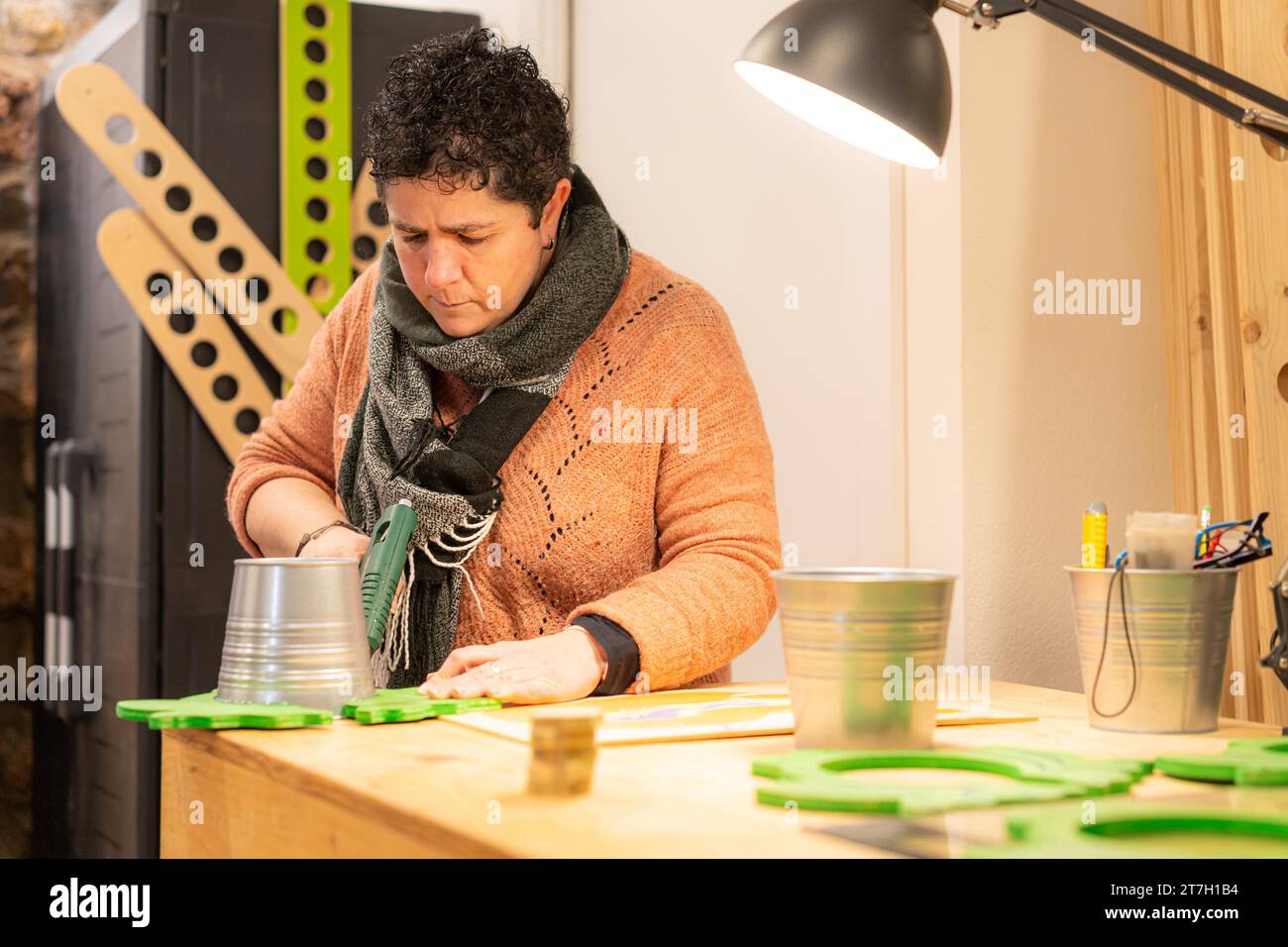 Woman using a tool to attach pieces of wood with glue in a workshop ...