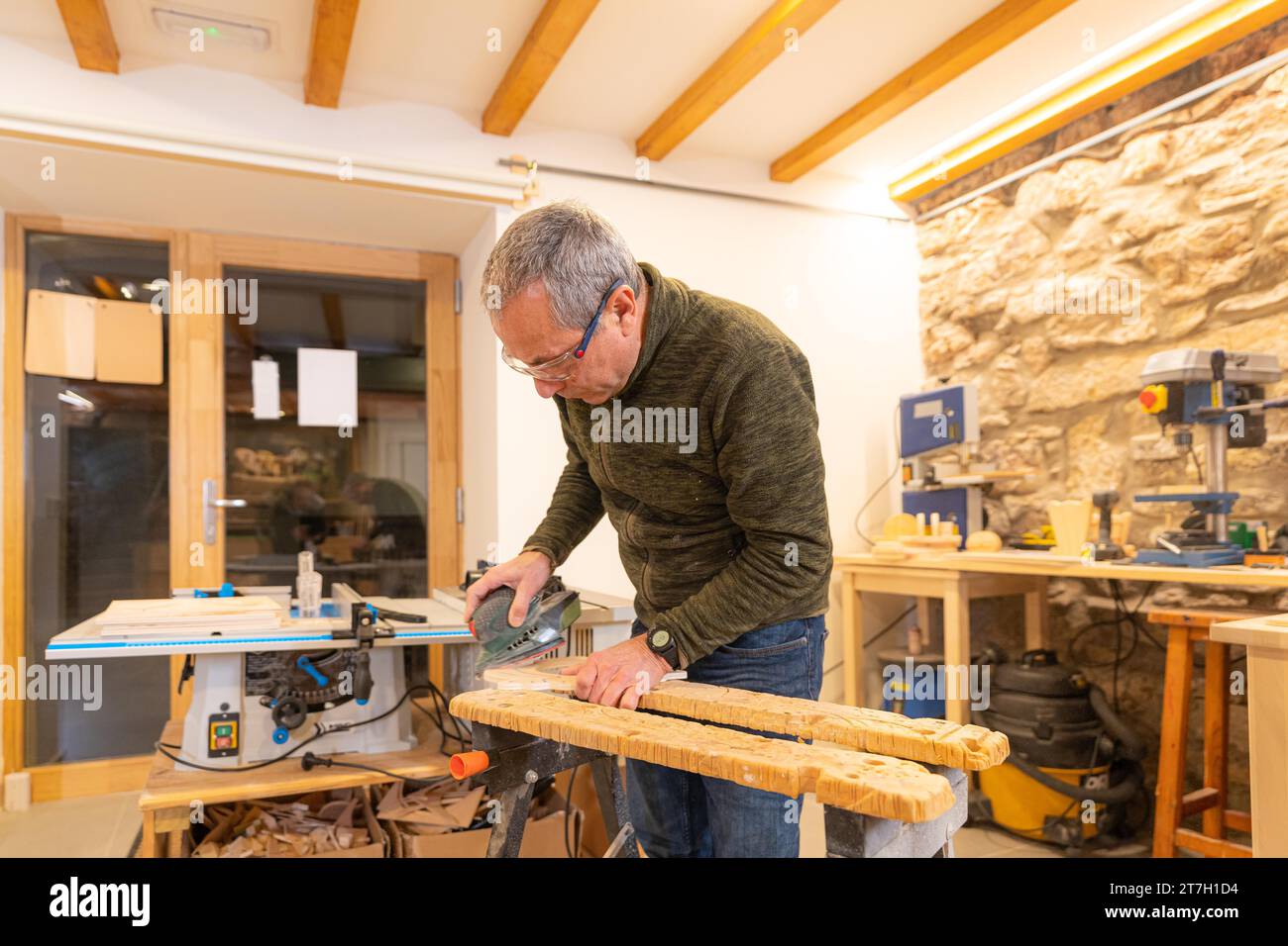 Carpenter using an electric tool to sanding a piece of wood in a ...