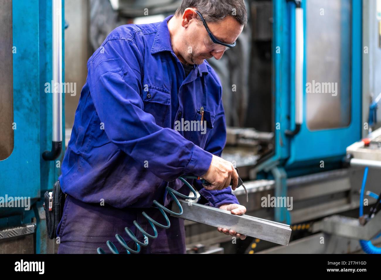 Factory worker operator in the numerical control sector cleaning a part ...