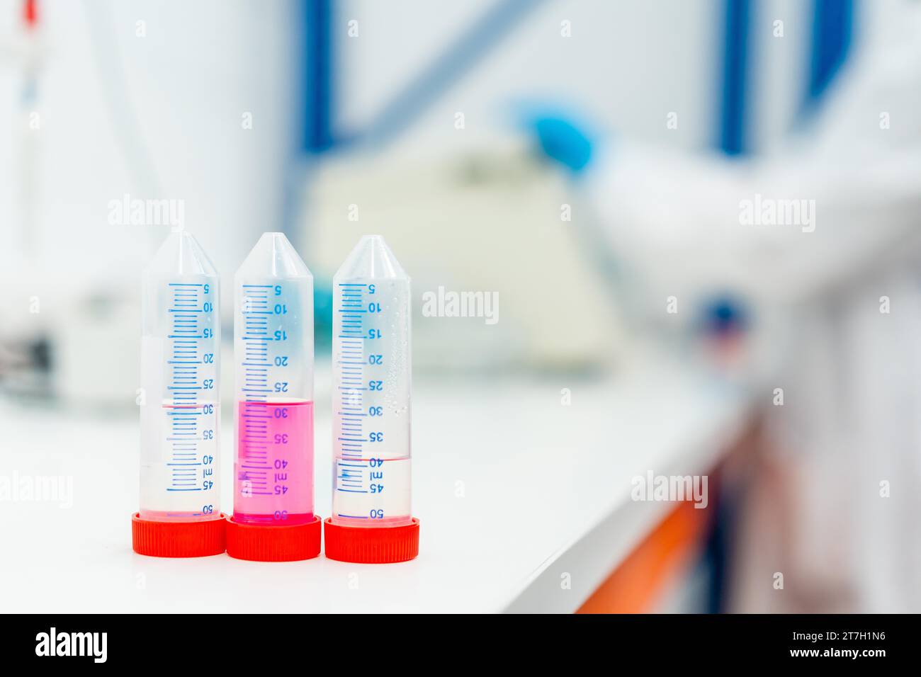 Three tubes with samples in the table of a laboratory with someone ...