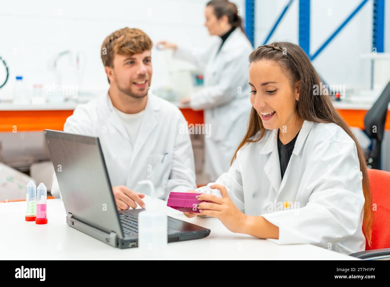 Two young and happy scientist using laptop during scholarship in the university laboratory Stock ...