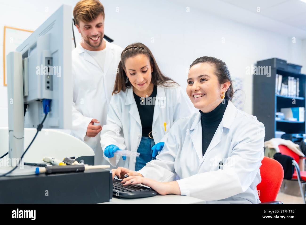 Three young doctors working in a scholarship in a laboratory using ...