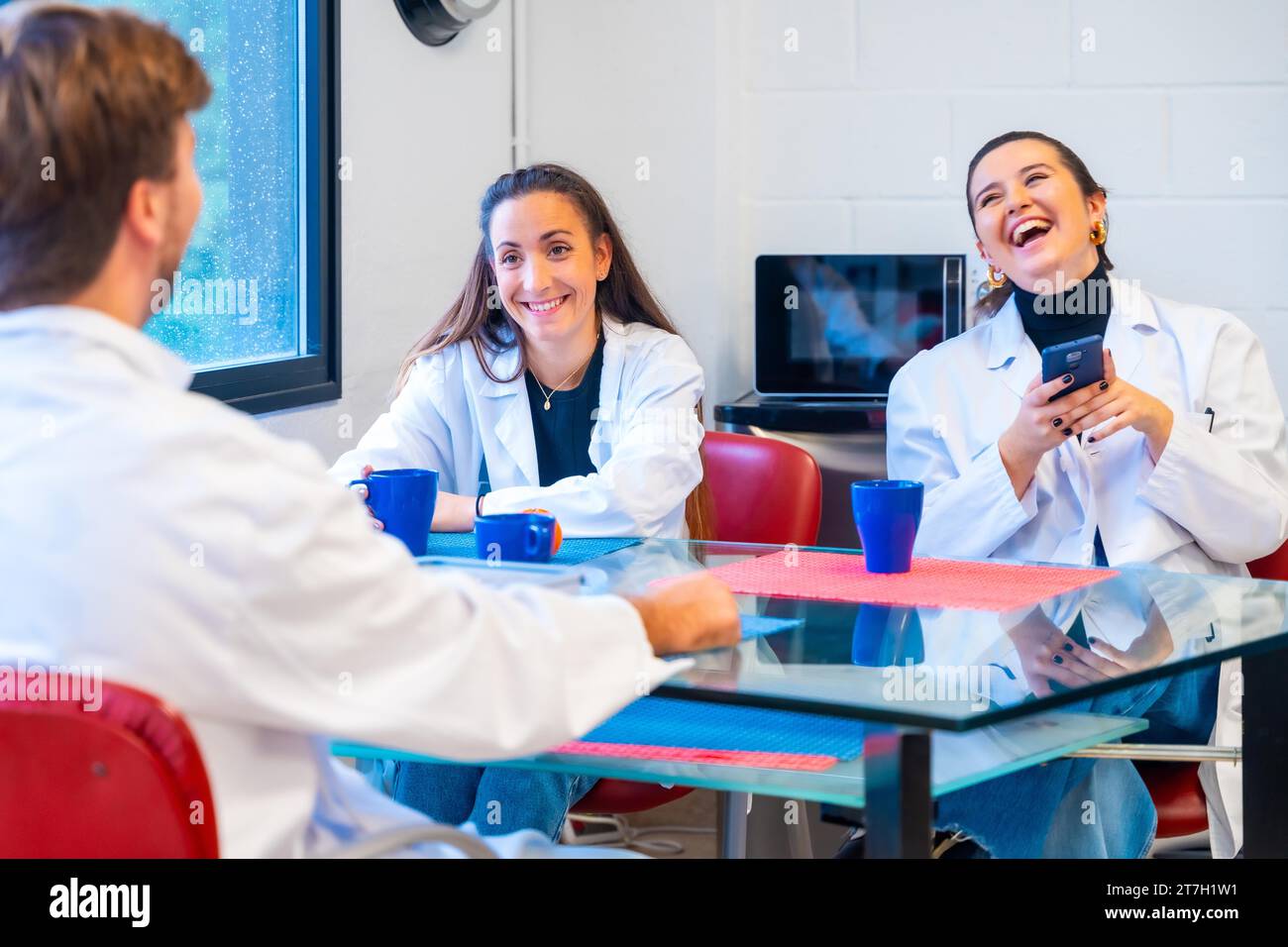 Group of three young scientists sitting and chatting during a coffee ...