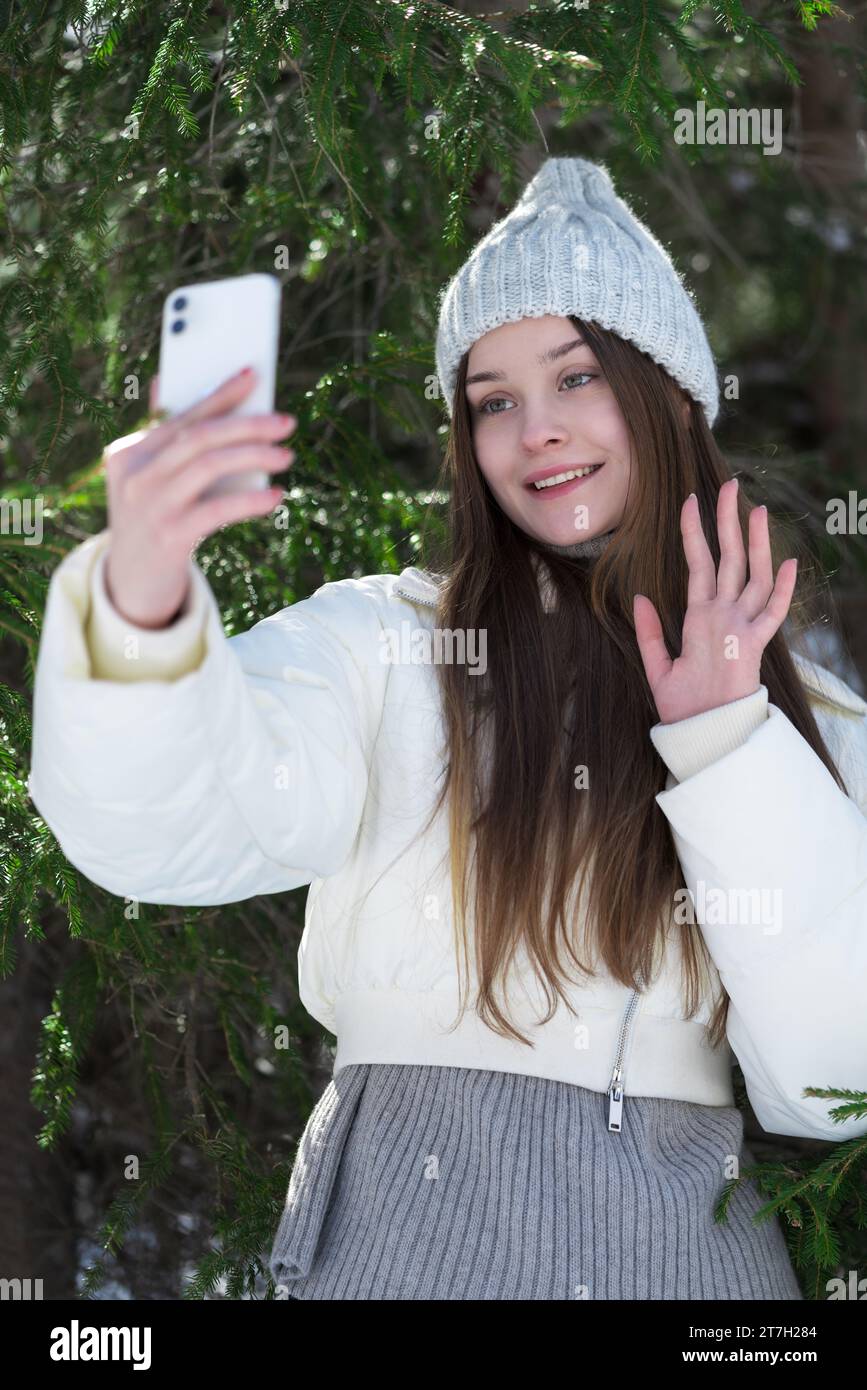 Playful teen girl using cellphone on pine forest, making selfie shoots ...