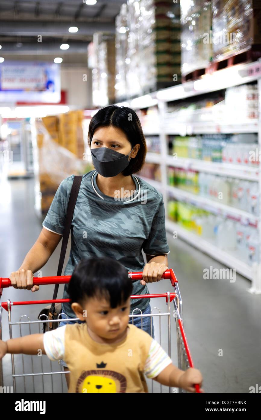Mother pushing shopping cart with her infant baby boy child down ...