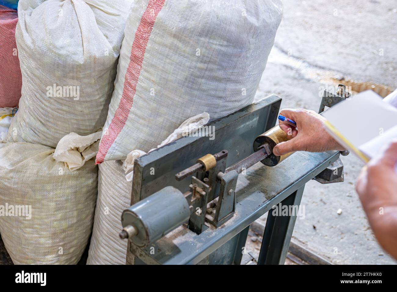 man handsholding pen in front of scale weighing packs ,weighing sacks ...