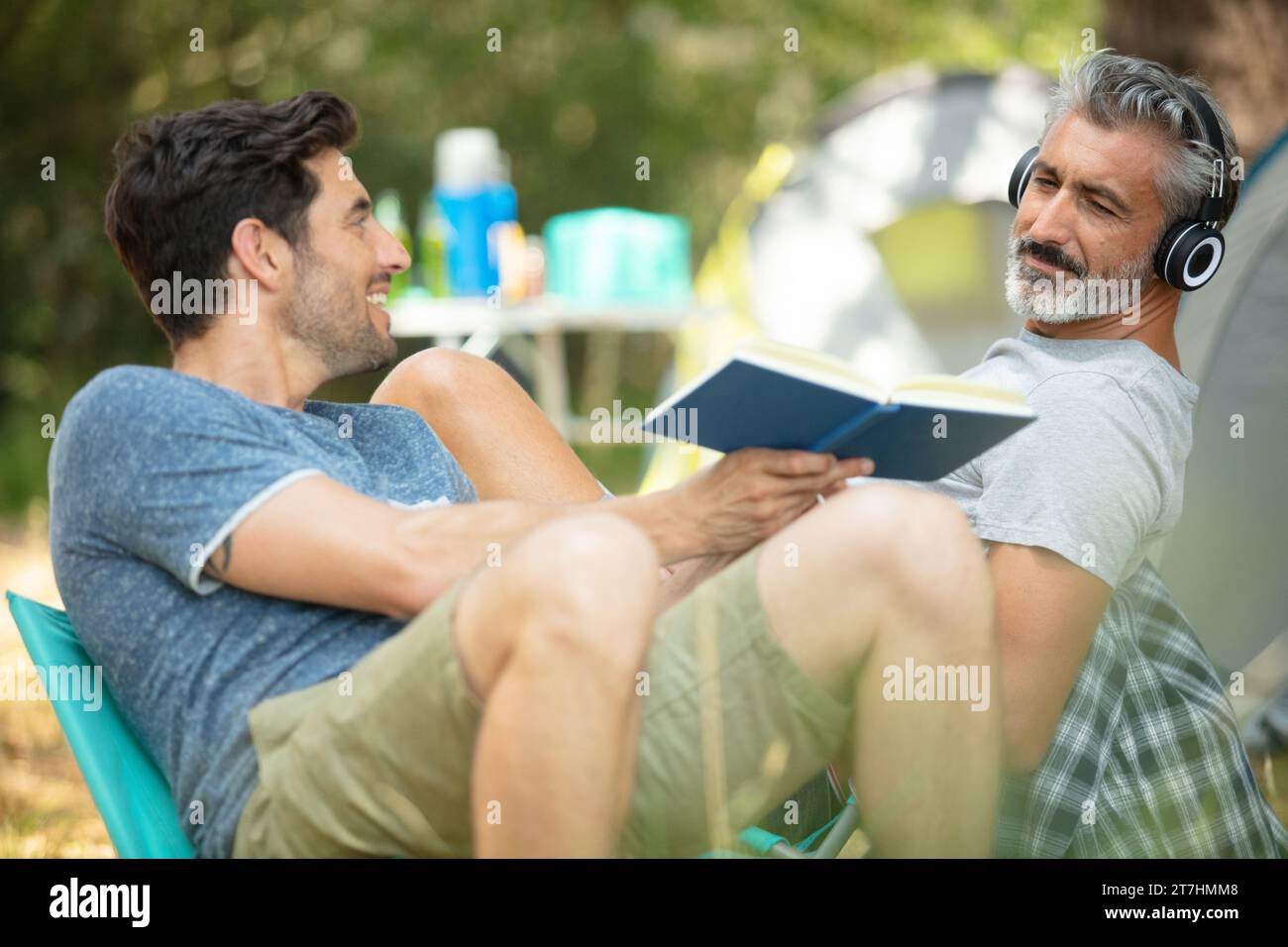 camping man reading a book with friend Stock Photo - Alamy
