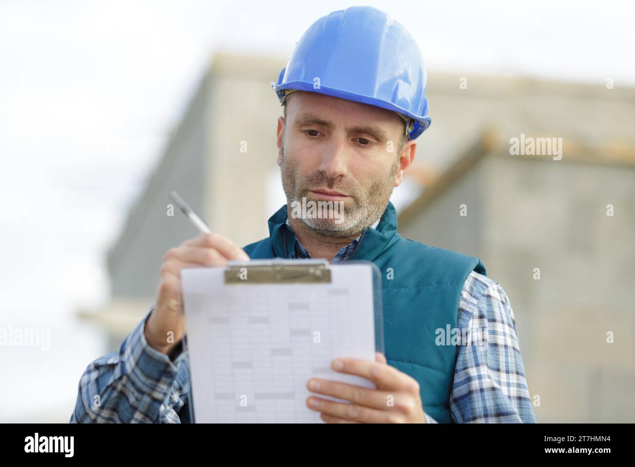 male builder writing on clipboard Stock Photo - Alamy