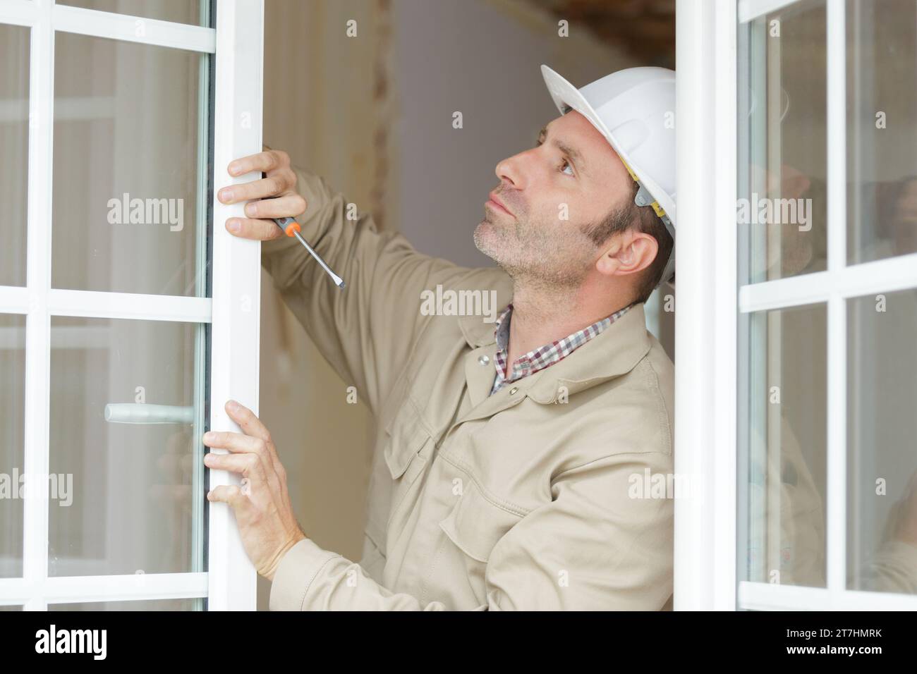 a construction worker fixing a window Stock Photo - Alamy