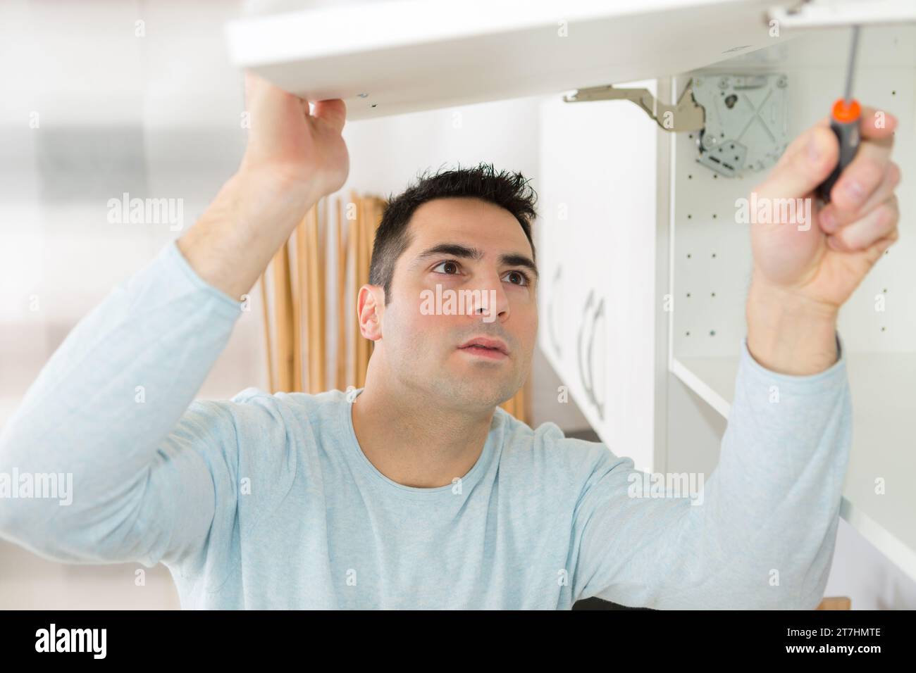 handyman fixing a door on the cupboard Stock Photo - Alamy