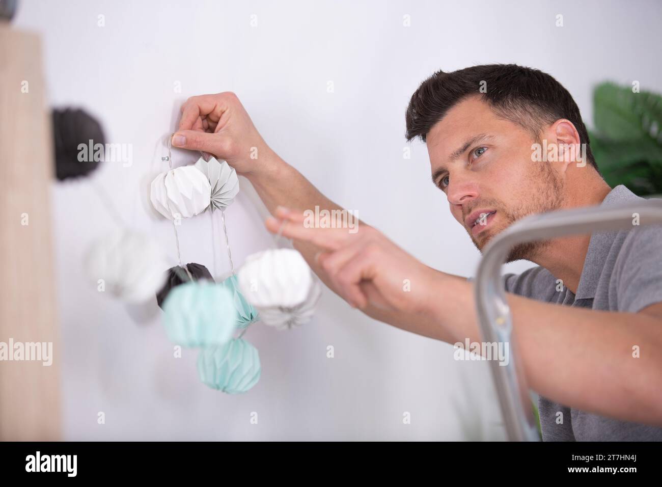 man putting up a garland indoors Stock Photo - Alamy
