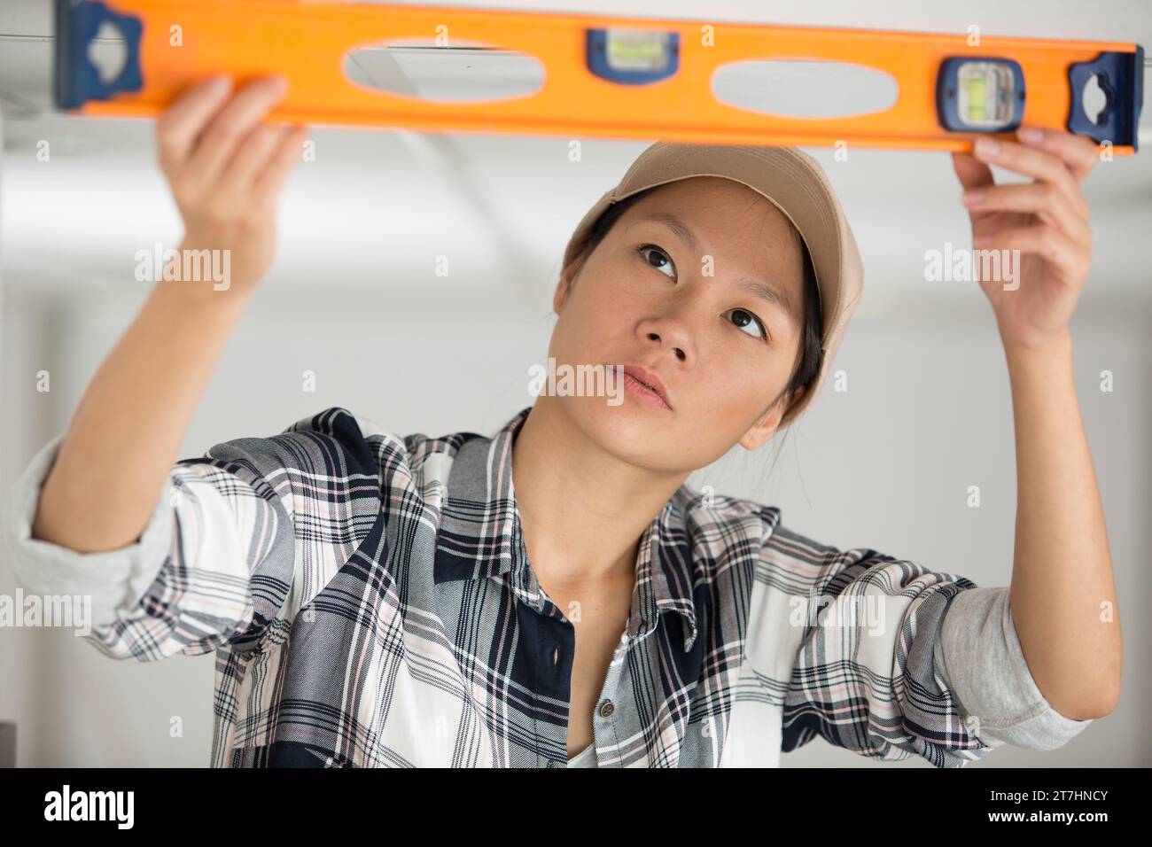 young woman using spirit level on ceiling Stock Photo - Alamy