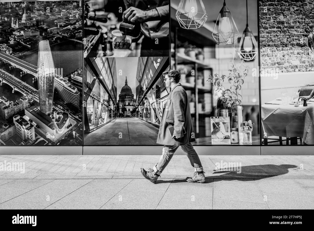 A man walking on a busy city sidewalk, passing by a large window with ...
