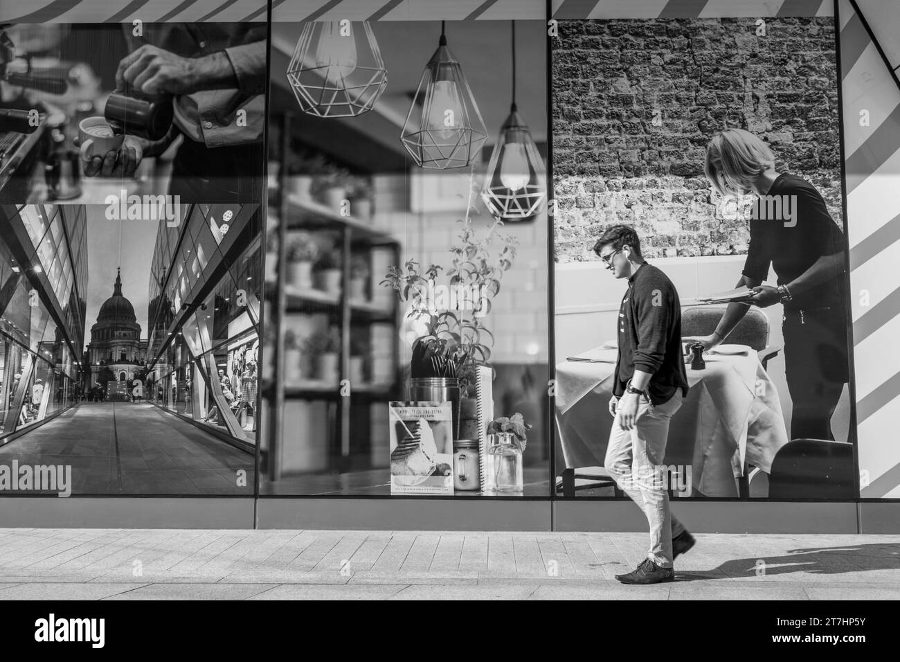 A man walking on a busy city sidewalk, passing by a large window with ...