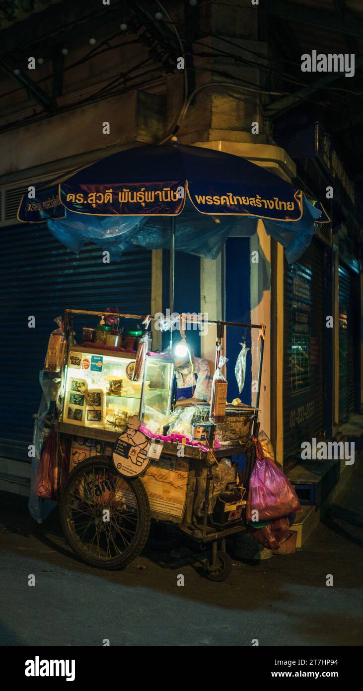 An outdoor food stall is situated in the middle of a street, providing ...