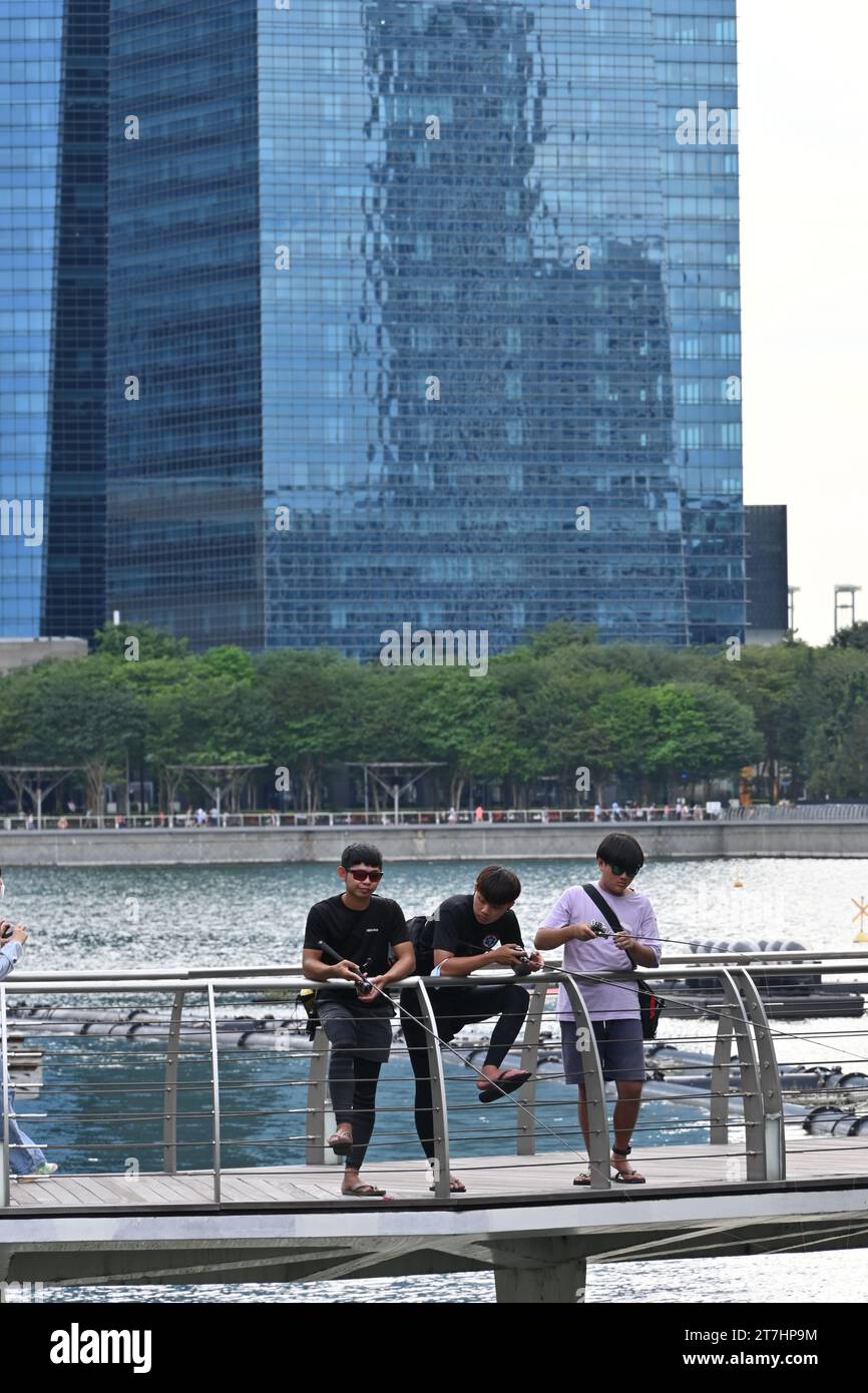 Three guys fishing in Marina Bay, one of the main business areas in the ...
