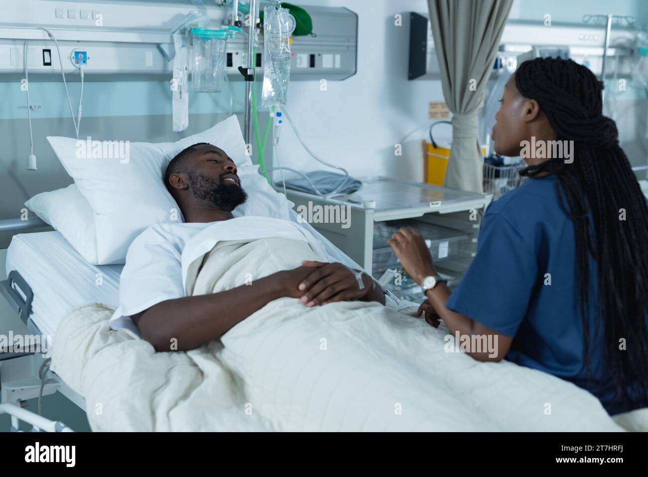 African american female doctors and male patient is lying in bed ...
