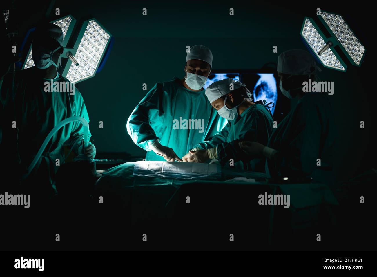 Diverse surgeons wearing surgical gowns operating on patient in ...