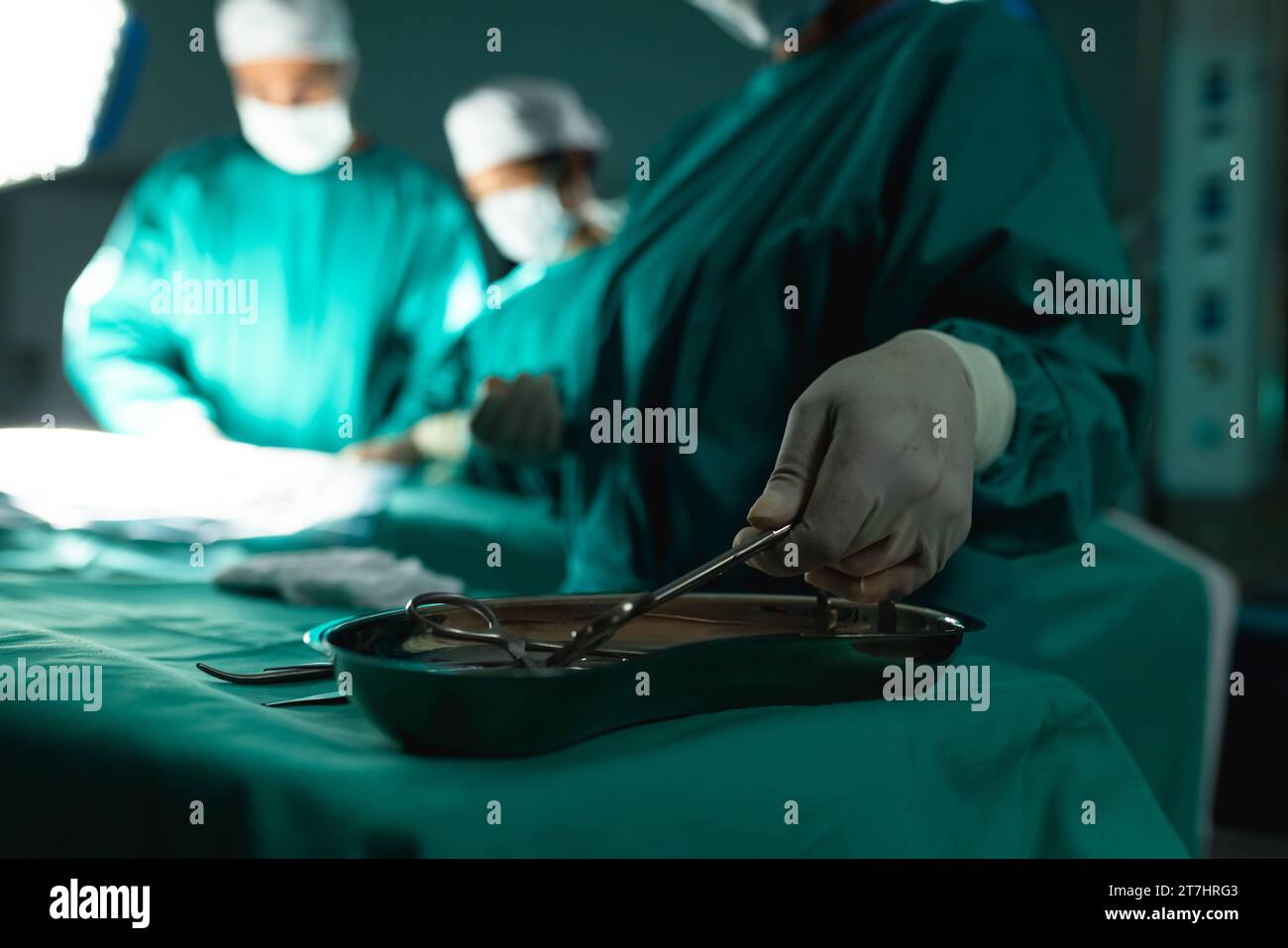 Diverse surgeons wearing surgical gowns using surgical instruments in ...