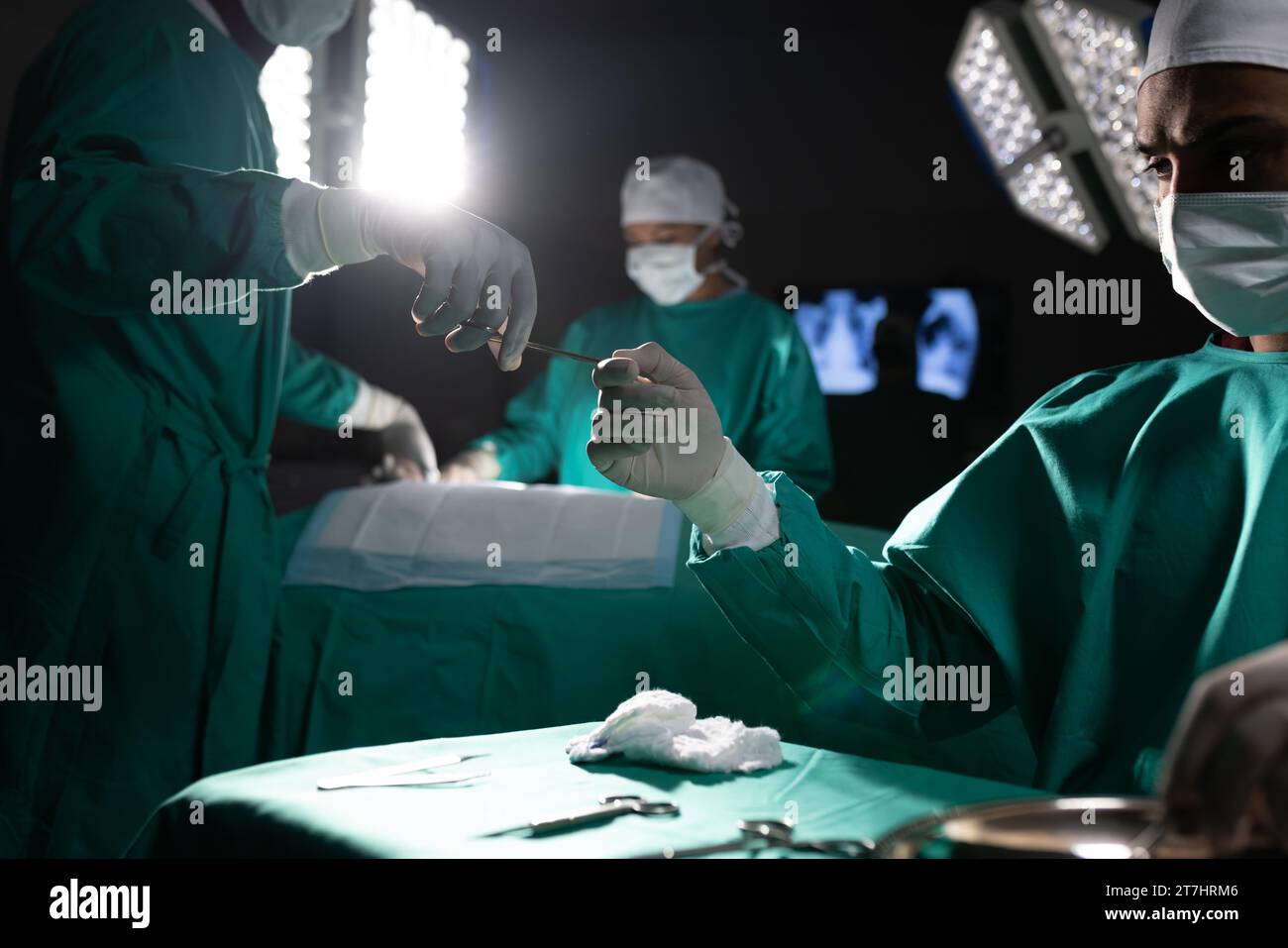 Diverse surgeons wearing surgical gowns using surgical instruments in ...
