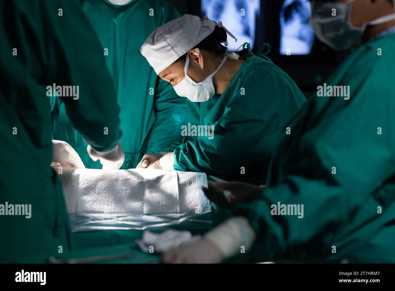 Diverse surgeons wearing surgical gowns operating on patient in ...