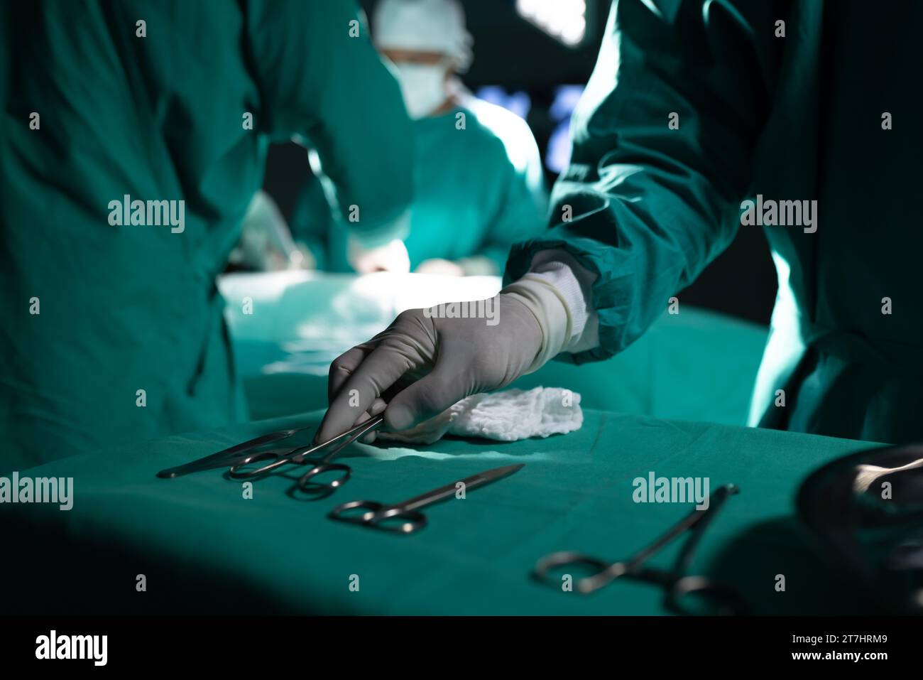 Diverse surgeons wearing surgical gowns using surgical instruments in ...