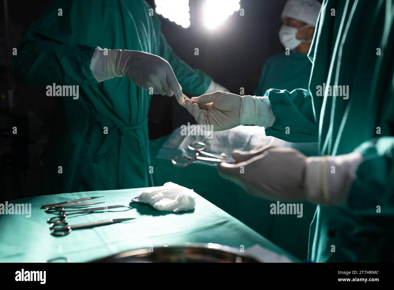 Diverse surgeons wearing surgical gowns using surgical instruments in ...