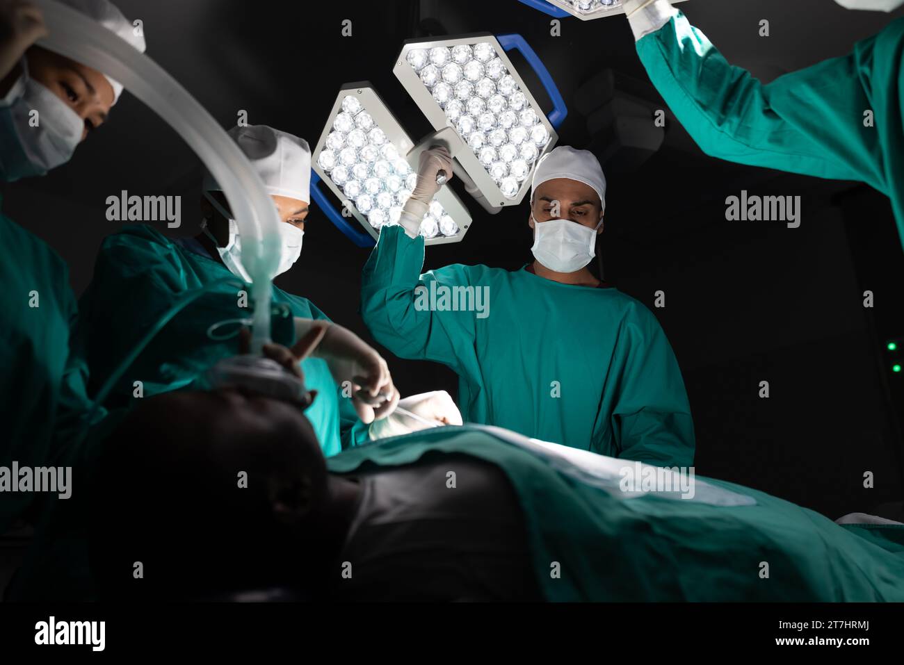 Diverse surgeons wearing surgical gowns operating on patient in ...