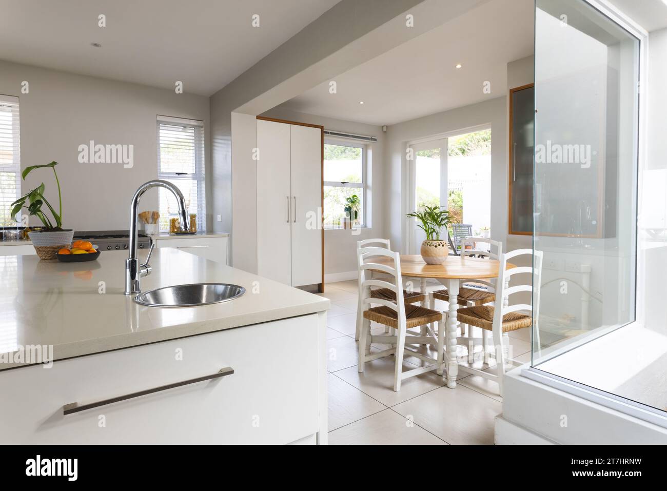 Kitchen island, sink, furniture and large windows in sunny kitchen at ...