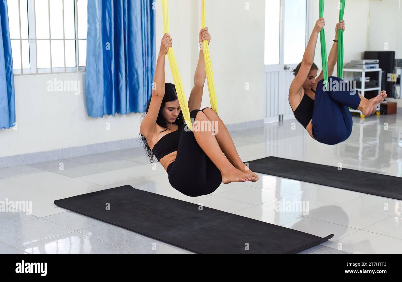 Yoga instructor helping a woman make aerial or fly yoga pose Stock ...