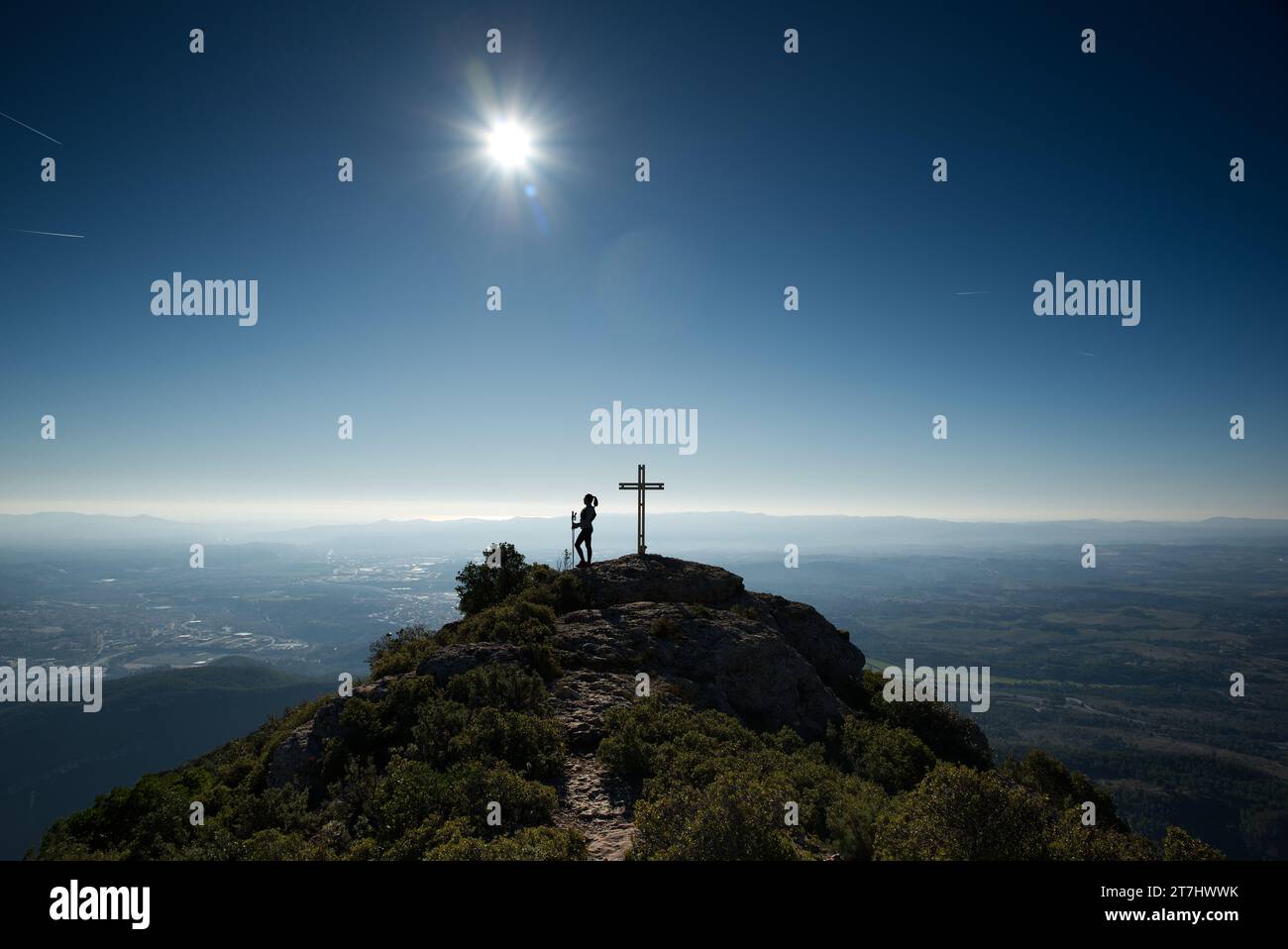 Woman contemplates the imposing landscape next to a cross from the top ...