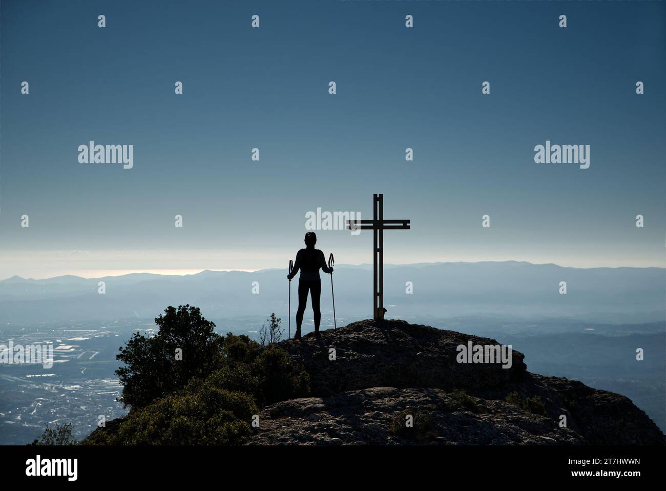Woman contemplates the imposing landscape next to a cross from the top ...