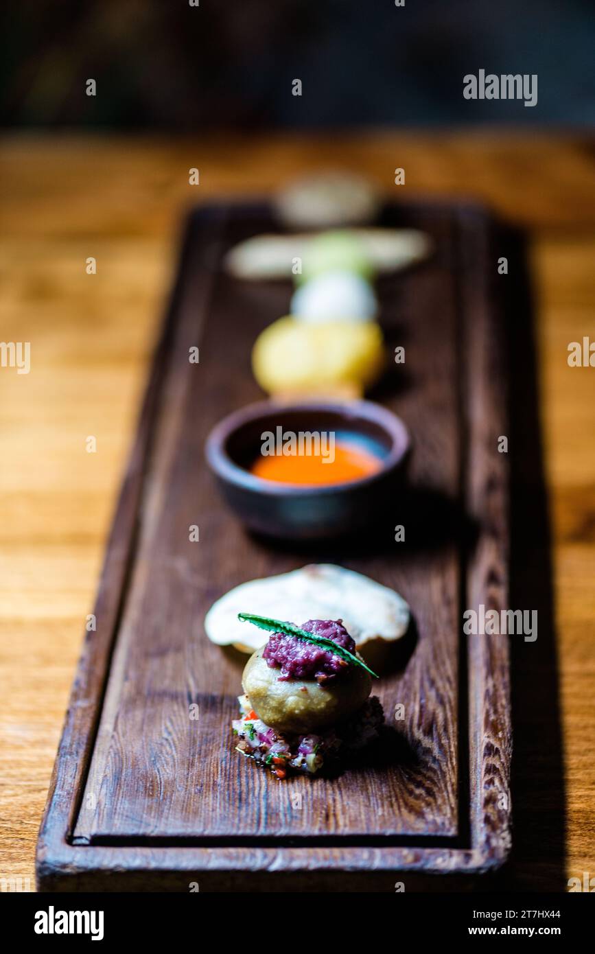 A rustic wooden tray filled with various food items, including fruits ...