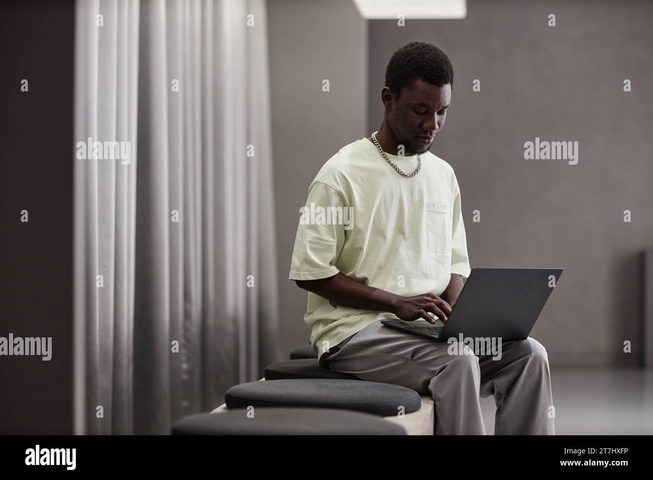 Graphic minimal portrait of young African American man using laptop at ...