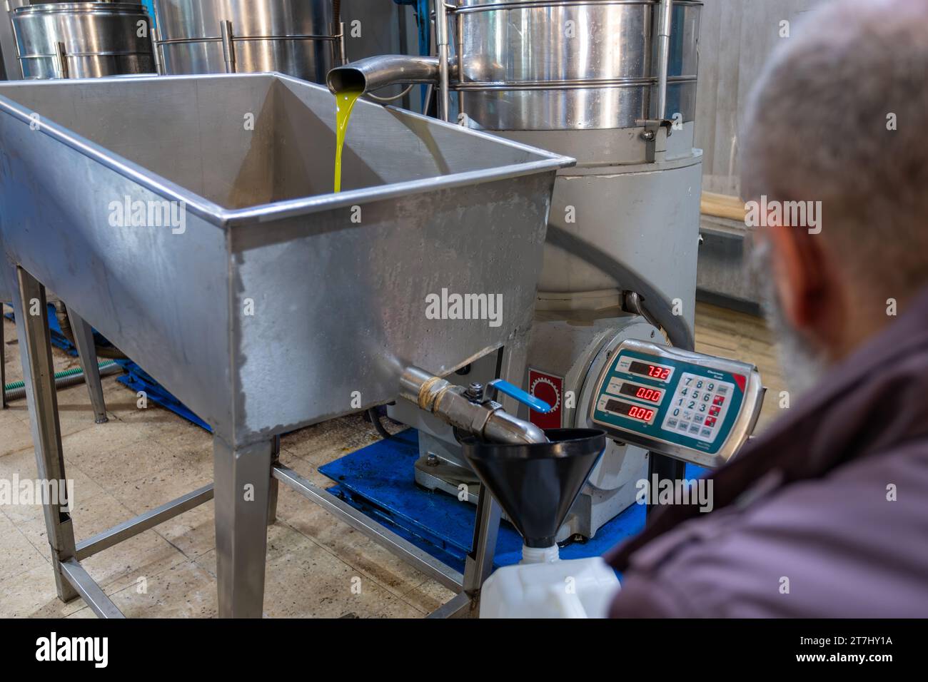 An old Muslim man is filling fresh olive oil into plastic gallons using ...