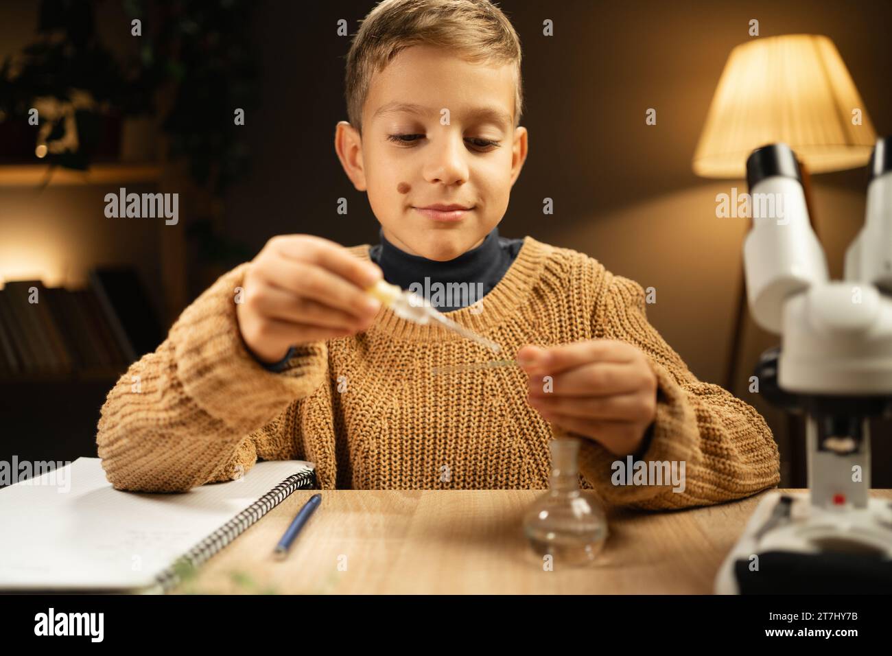 Cute boy looks into microscope. Child studying science in his room at ...