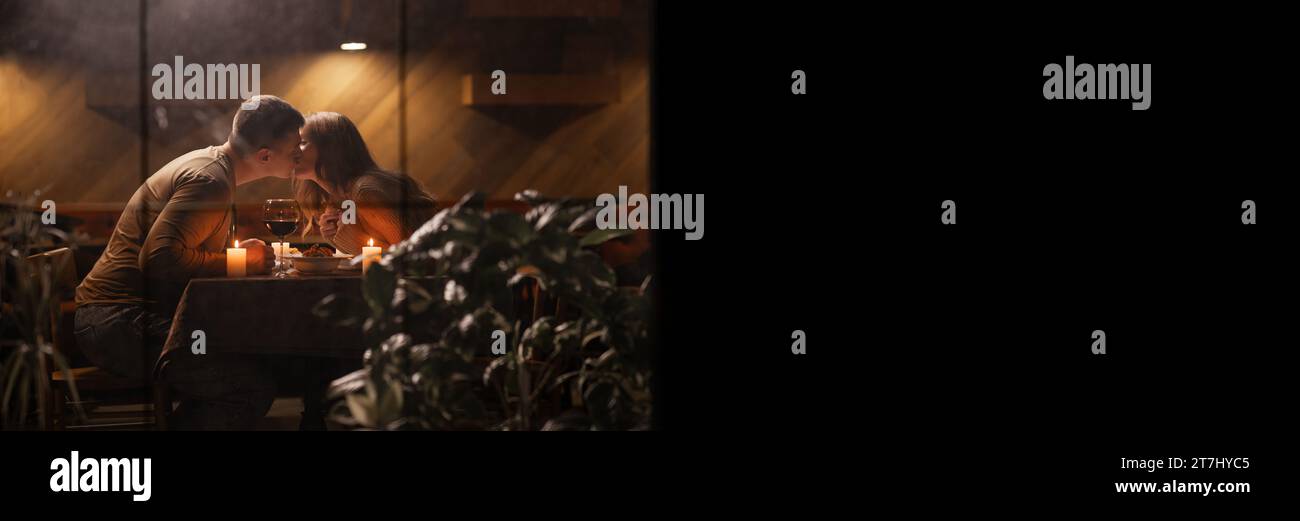 Romantic young couple kiss while during dinner at dining table ...