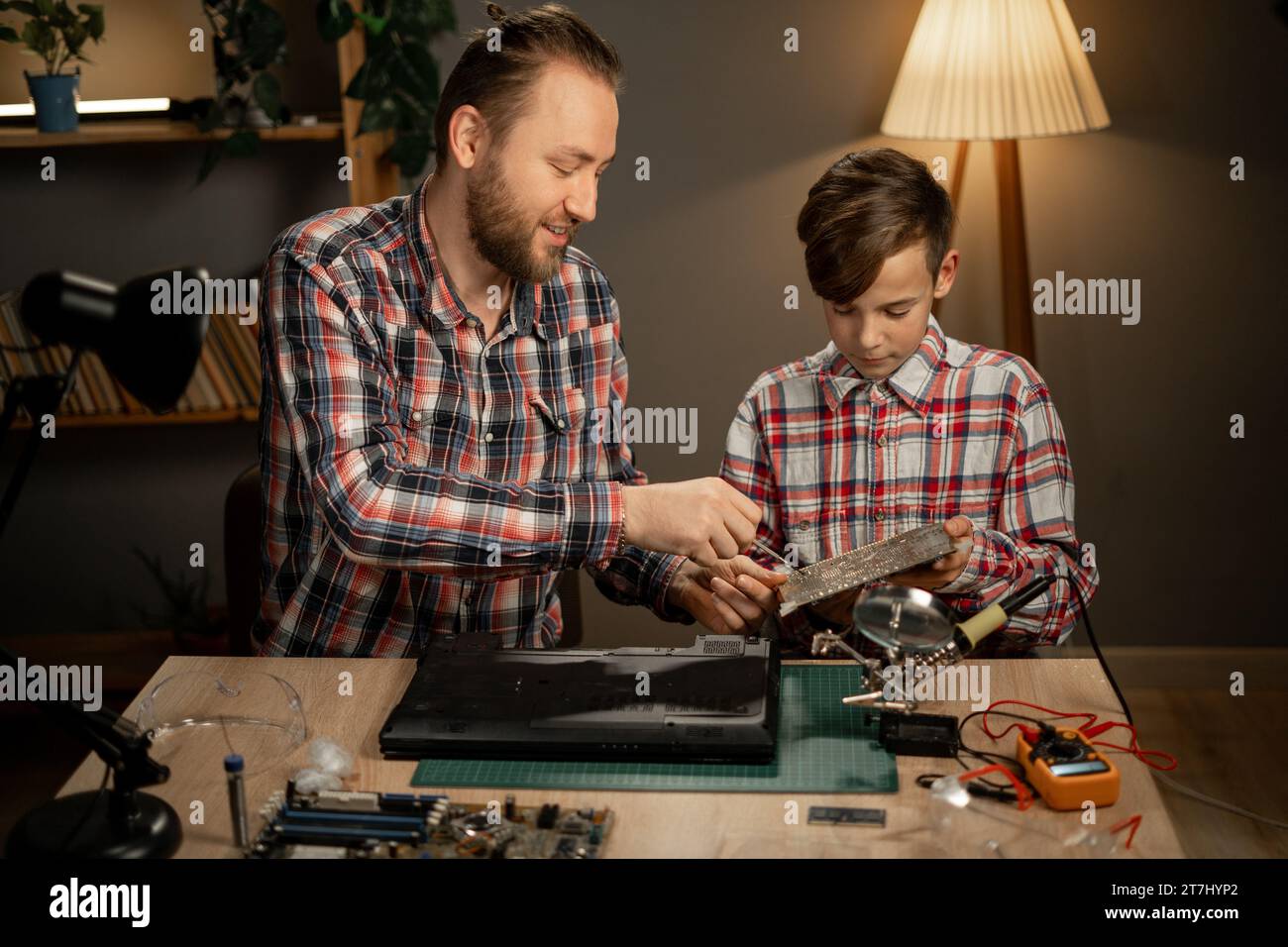 Happy boy and his father sitting together and repairing motherboard ...