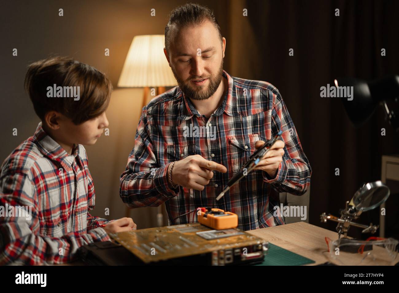 Caucasian father and his son using soldering iron for fixing ...
