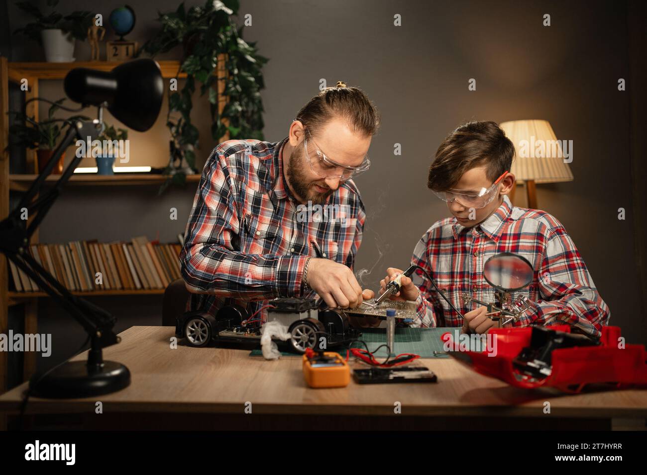 Dad and son wear and eyeglasses working with soldering iron while ...