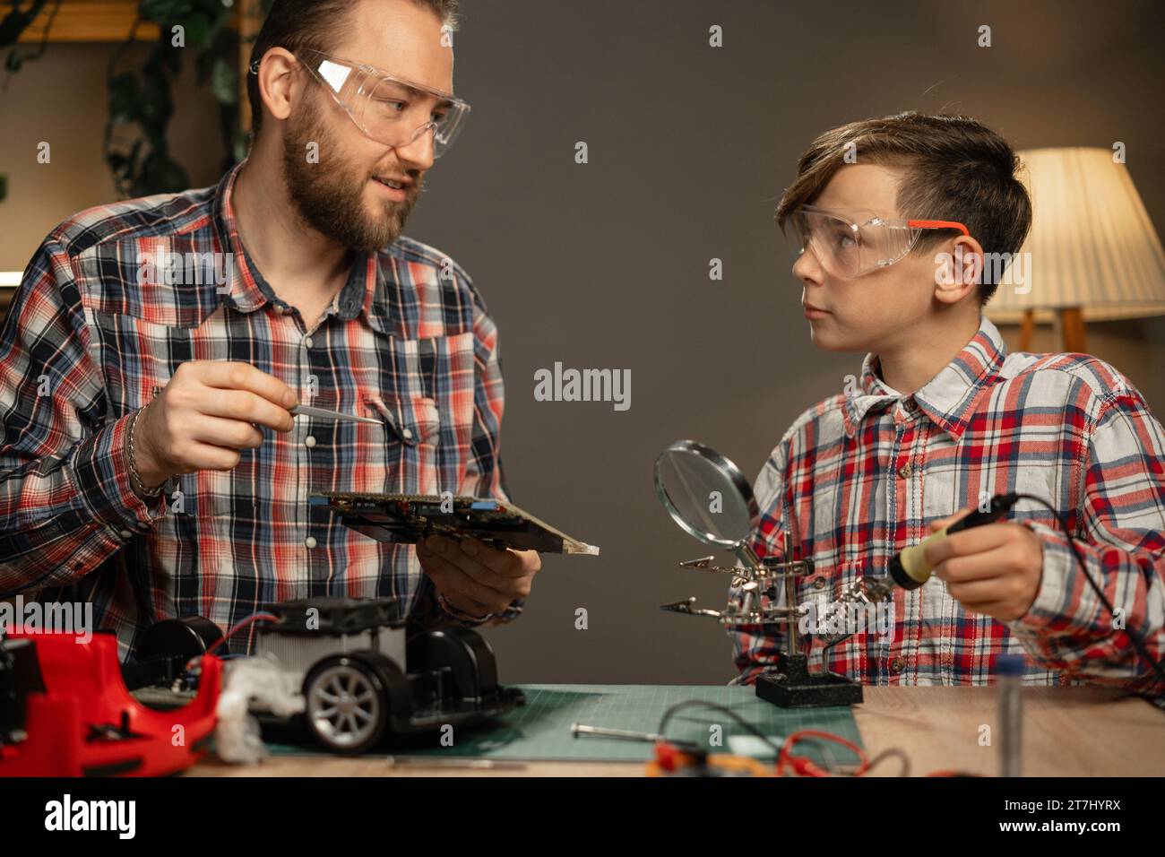 Happy father teaching his son for soldering remote controlled car at ...