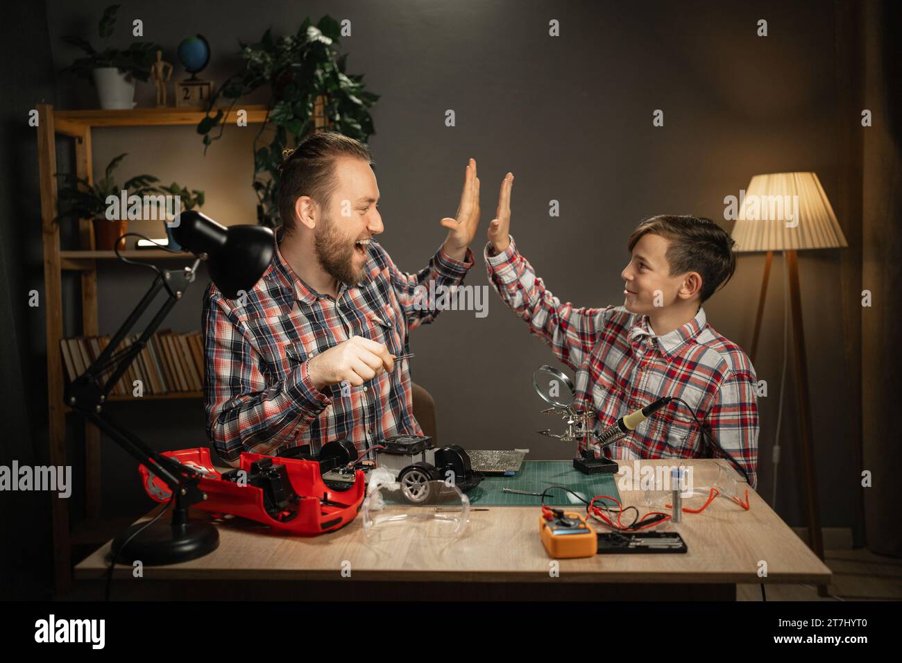 Teen boy giving high five to his father after fixing of electronic toy car. Concept of ...