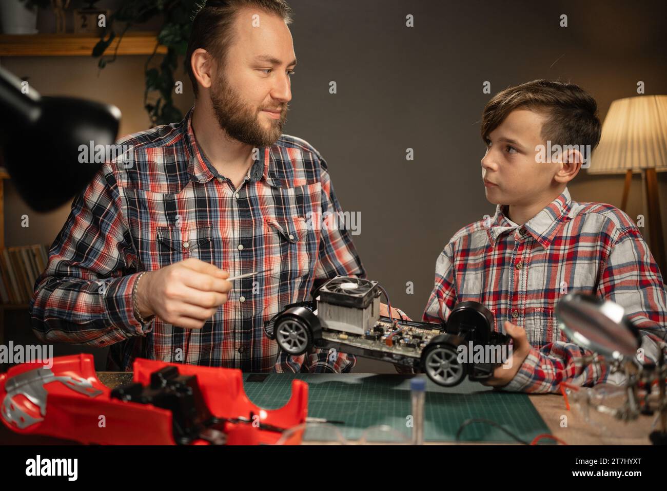 Young father teaching his son for soldering electrical car at home. Man ...