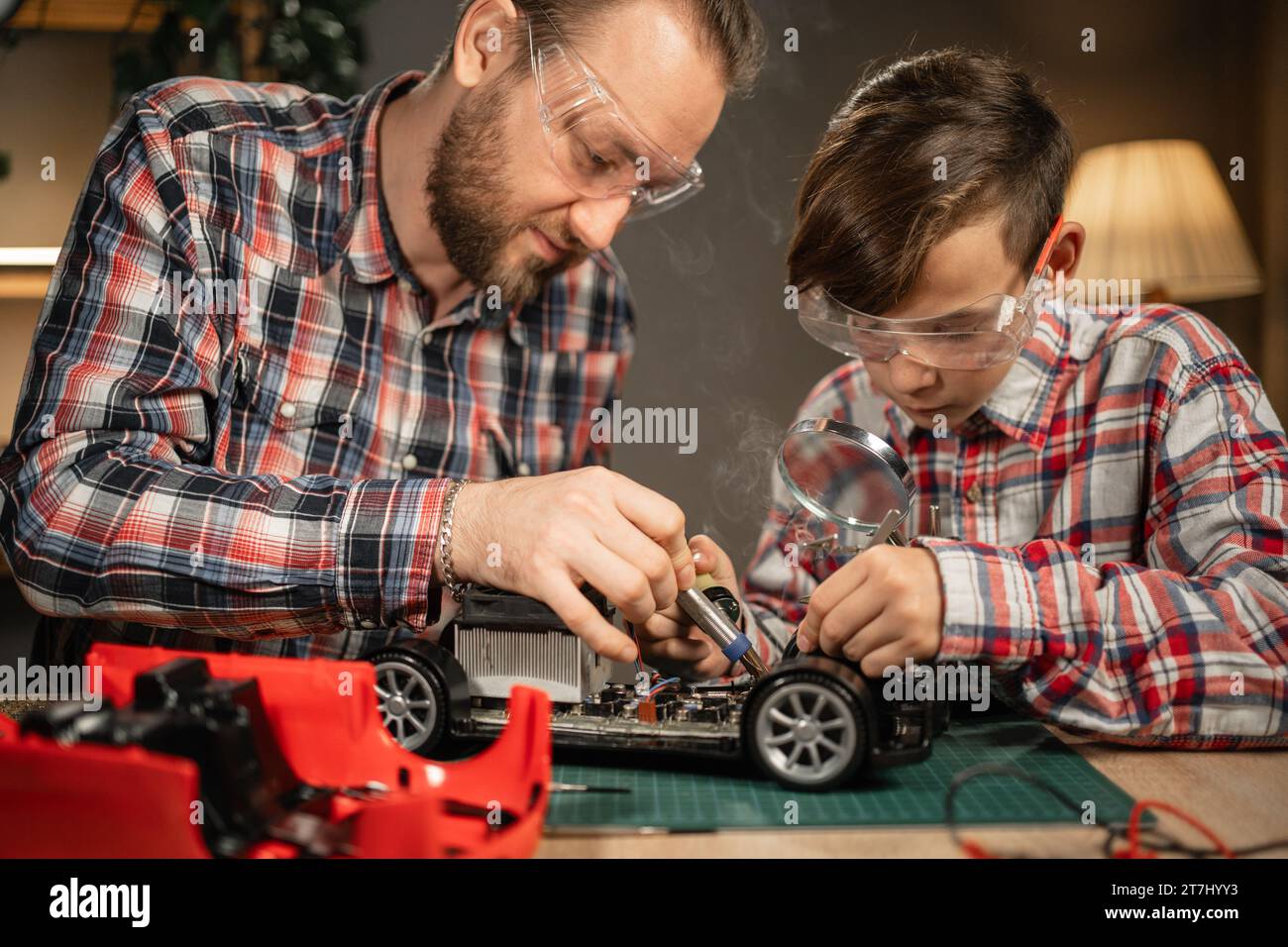 Father teaching his son for soldering and repair remote controlled car ...